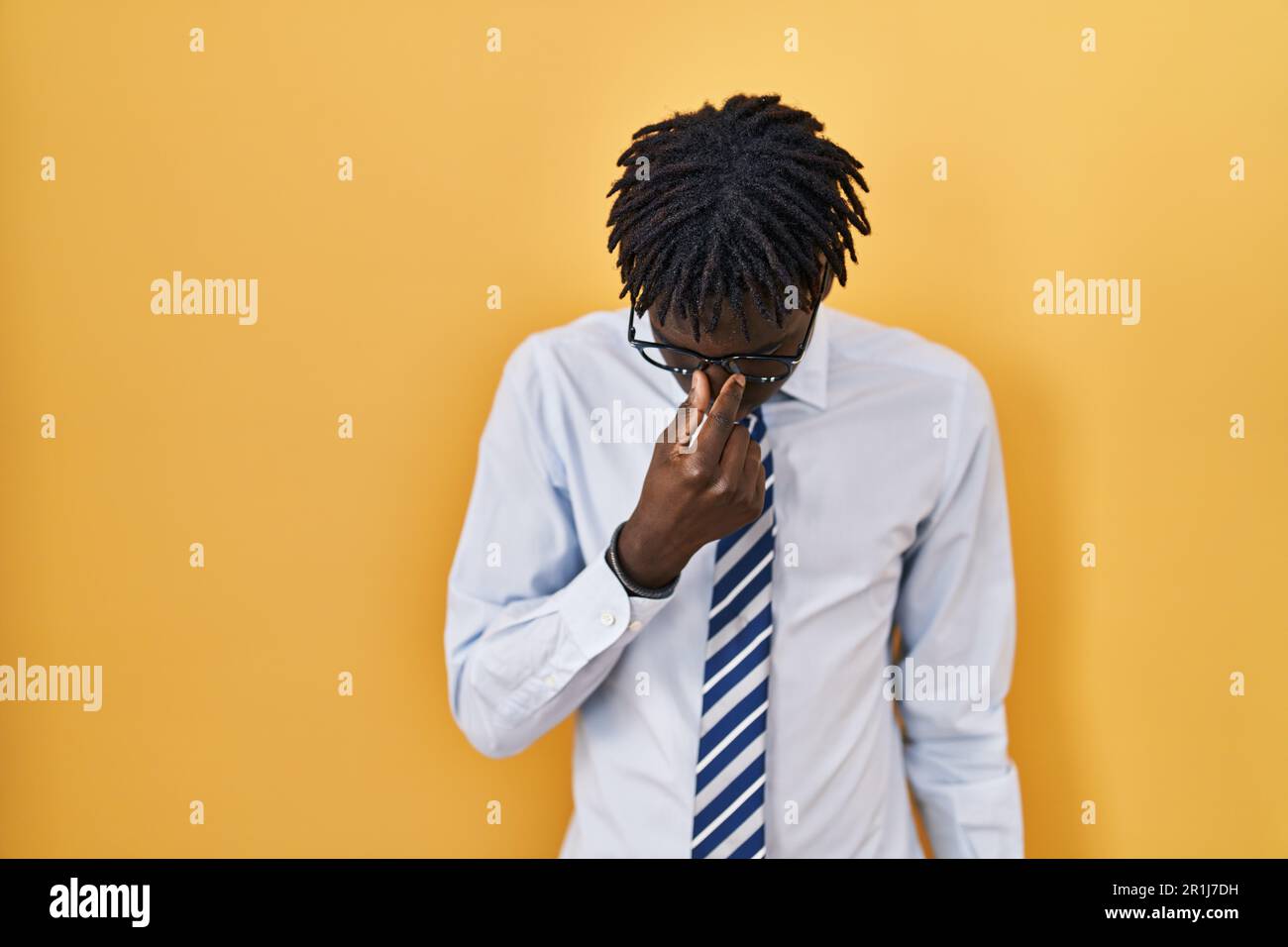 African man with dreadlocks standing over yellow background tired ...