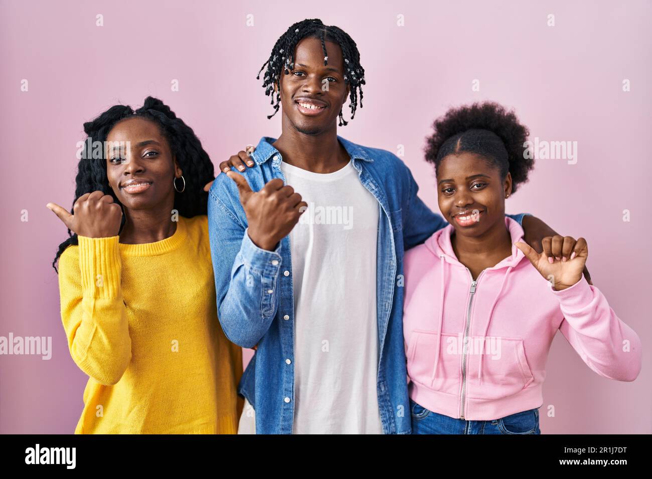 Group of three young black people standing together over pink ...