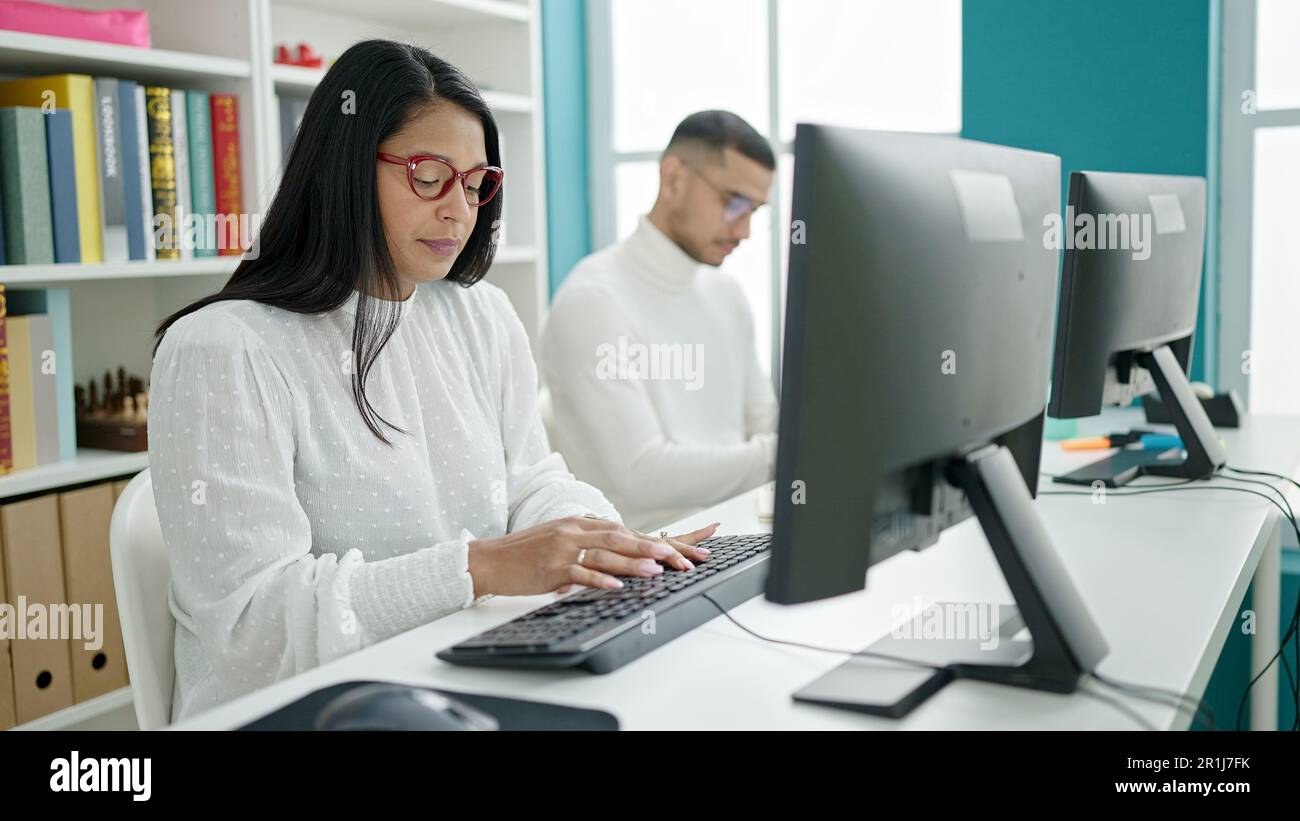 Man and woman students using computer studying at university classroom ...