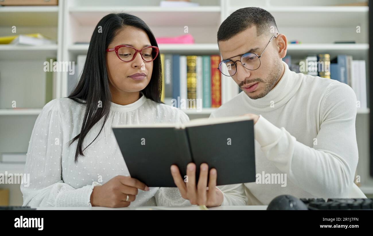 Man and woman students reading book studying at university classroom ...