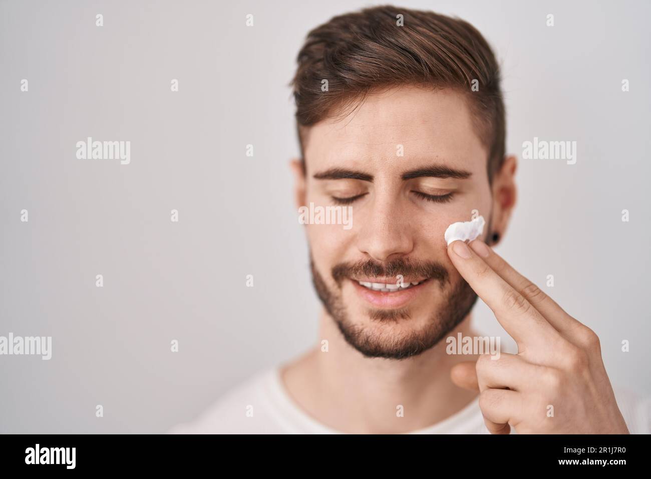 Hispanic Man With Beard Using Moisturizer Facial Cream Smiling With A