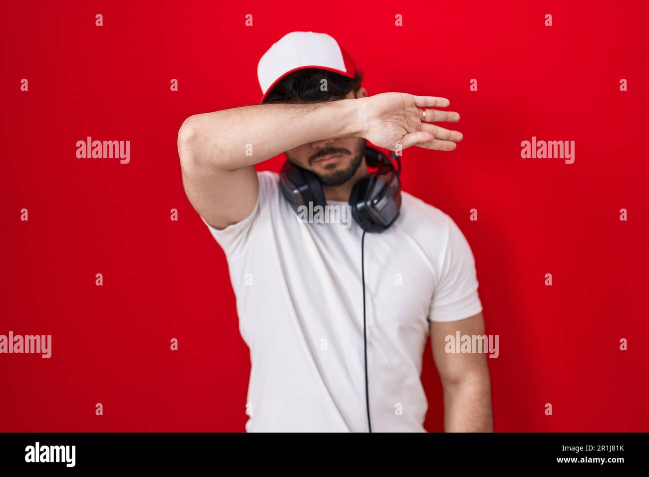 Hispanic man with beard wearing gamer hat and headphones covering eyes ...