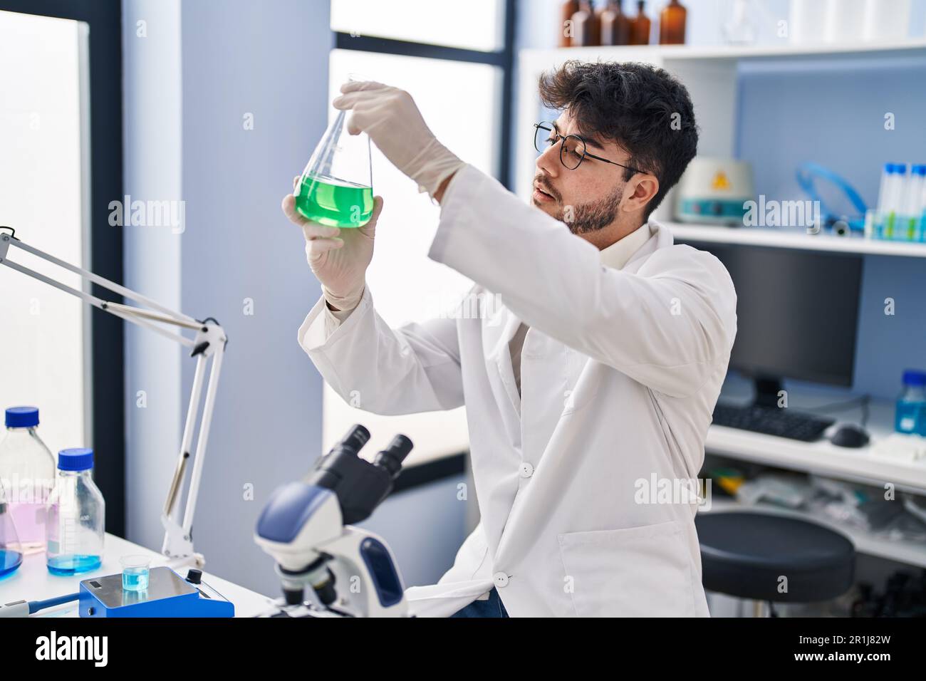 Young hispanic man scientist measuring liquid at laboratory Stock Photo ...