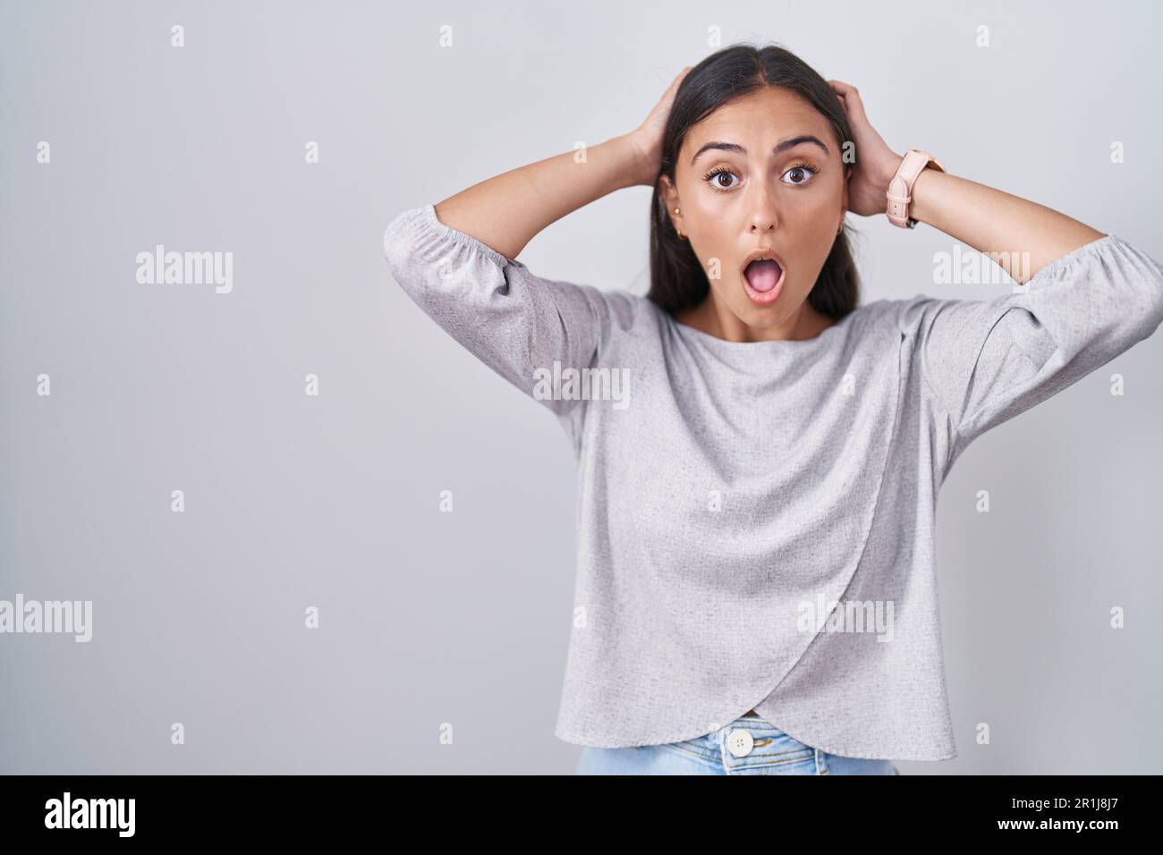 Young hispanic woman standing over white background crazy and scared ...