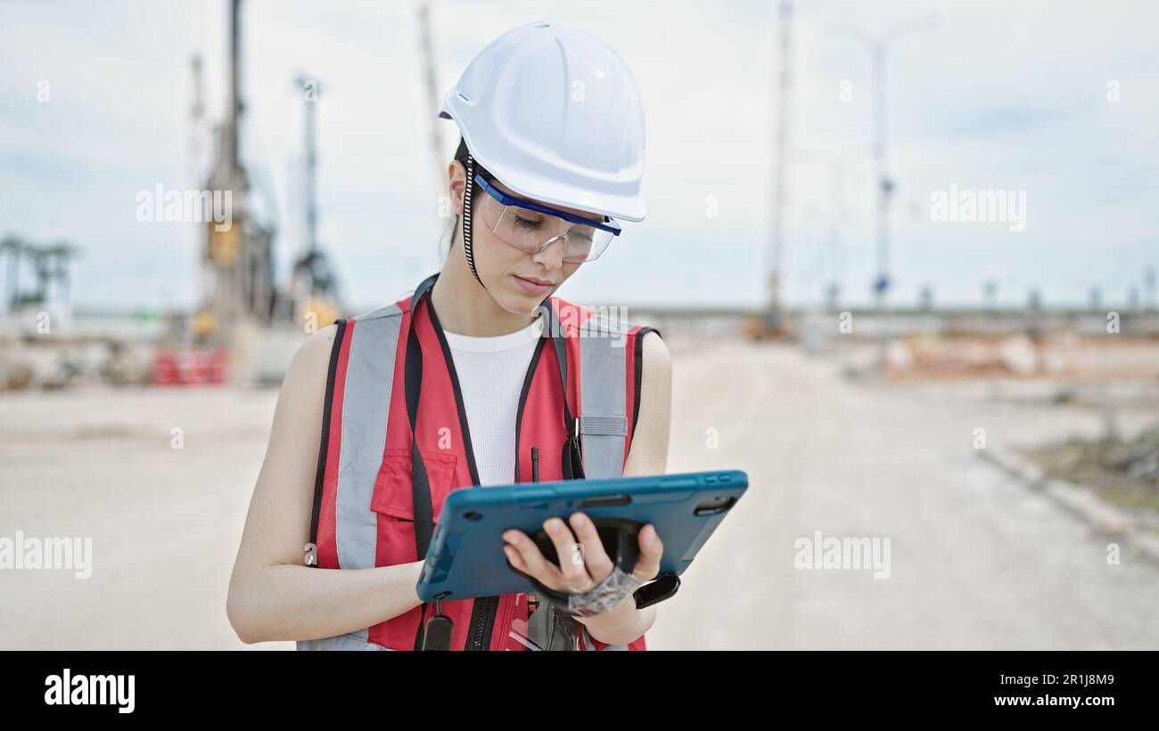 Young beautiful hispanic woman builder using touchpad at street Stock ...