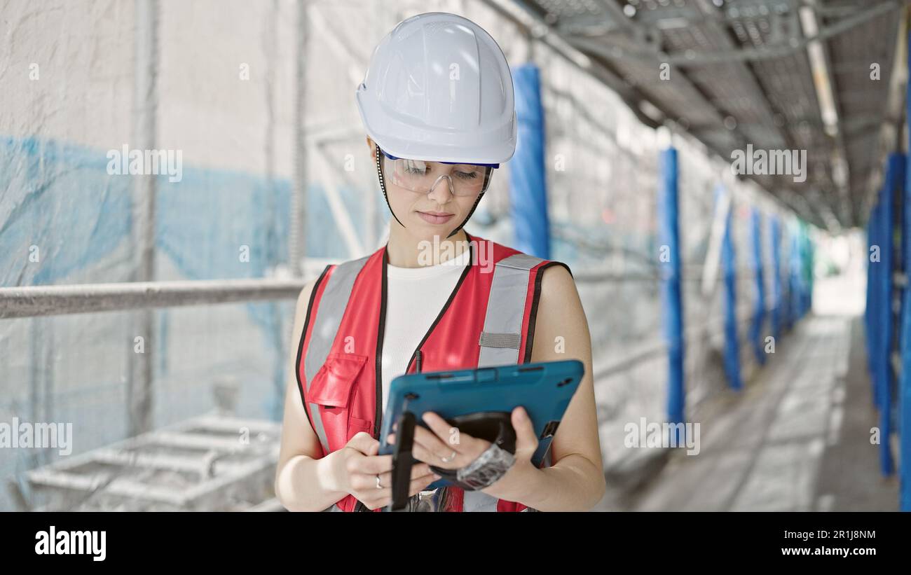 Young beautiful hispanic woman builder using touchpad at street Stock ...