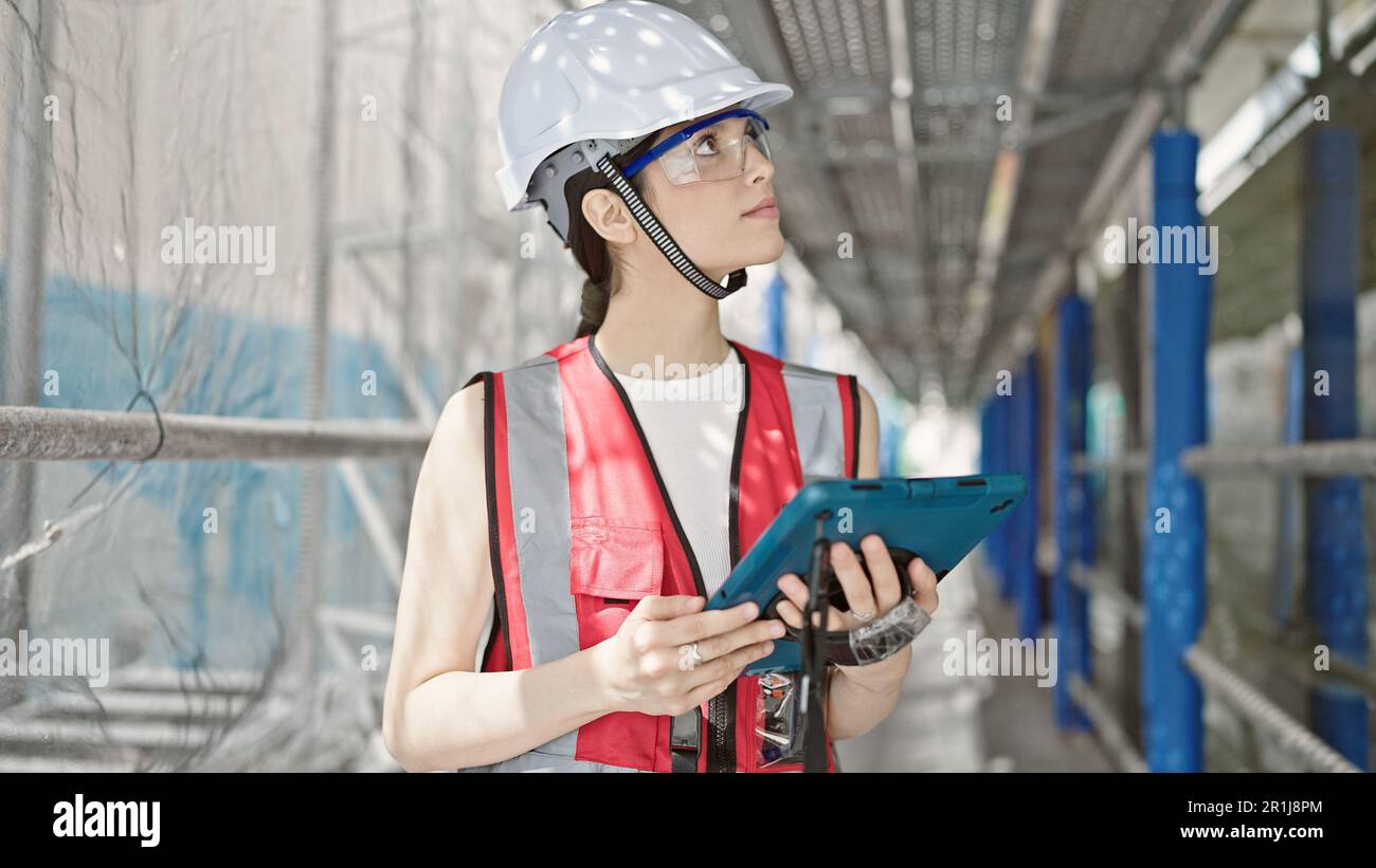 Young beautiful hispanic woman builder using touchpad at street Stock ...