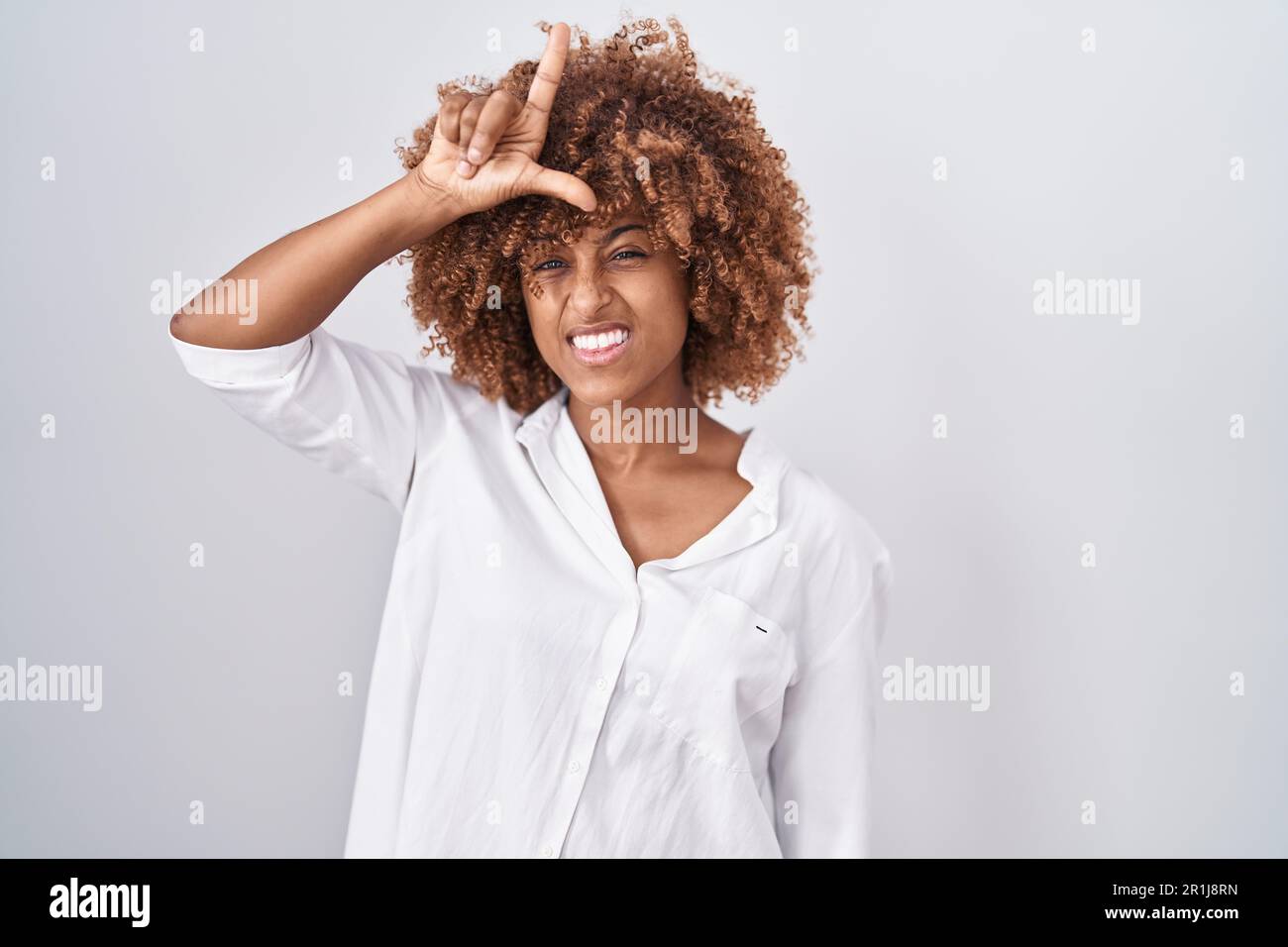 Young hispanic woman with curly hair standing over white background ...