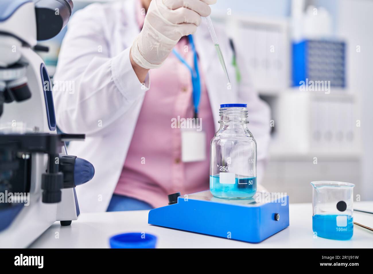 Young beautiful plus size woman scientist pouring liquid on test tube ...
