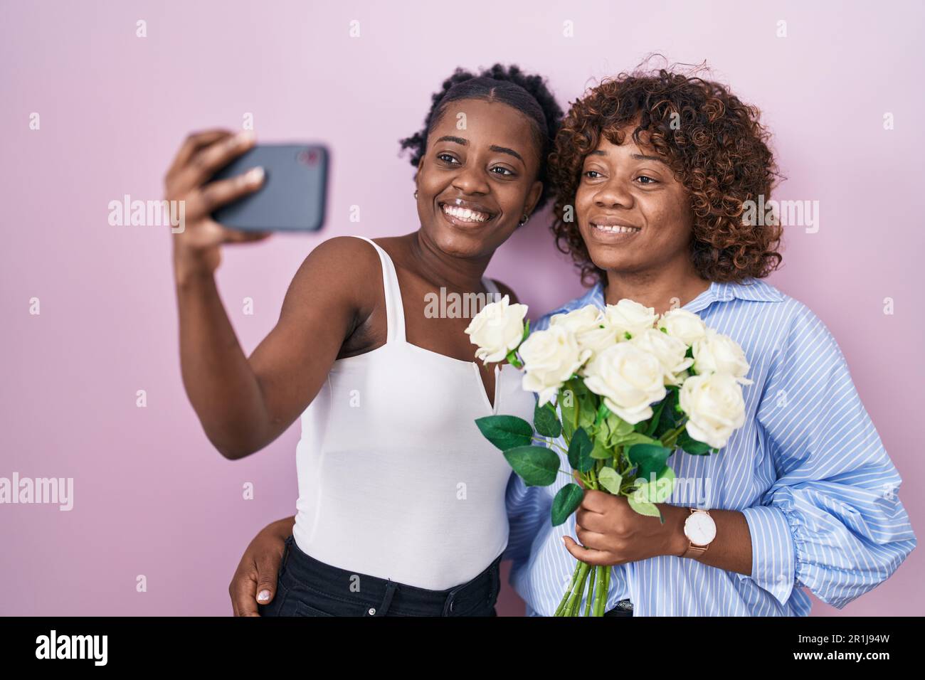 Two african women taking a selfie photo with flowers smiling with a ...