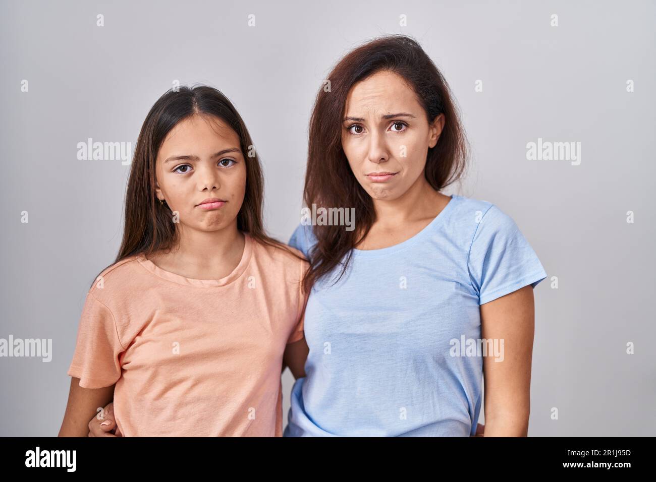 Young mother and daughter standing over white background depressed and ...