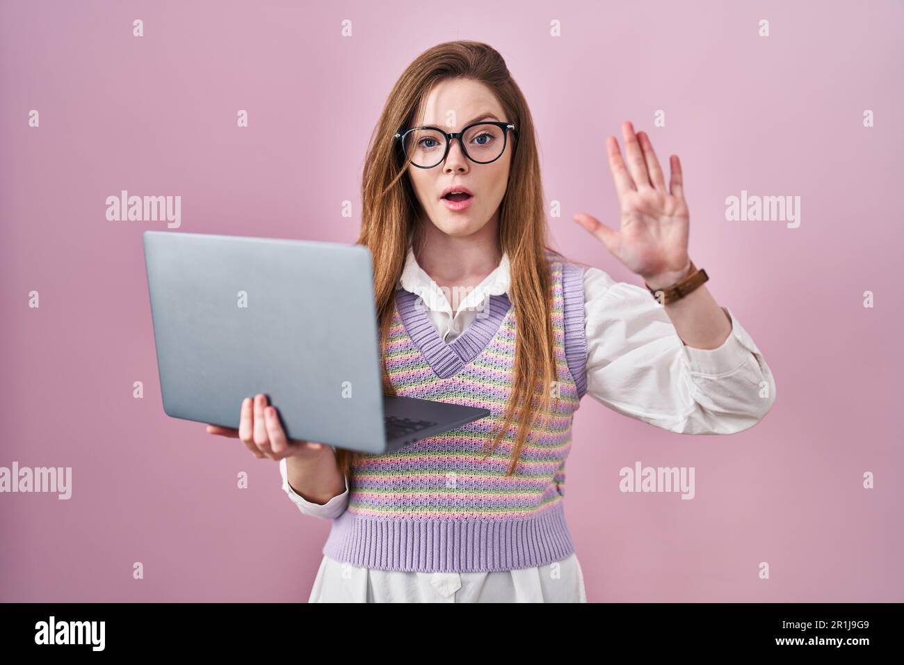 Young caucasian woman working using computer laptop doing stop gesture ...