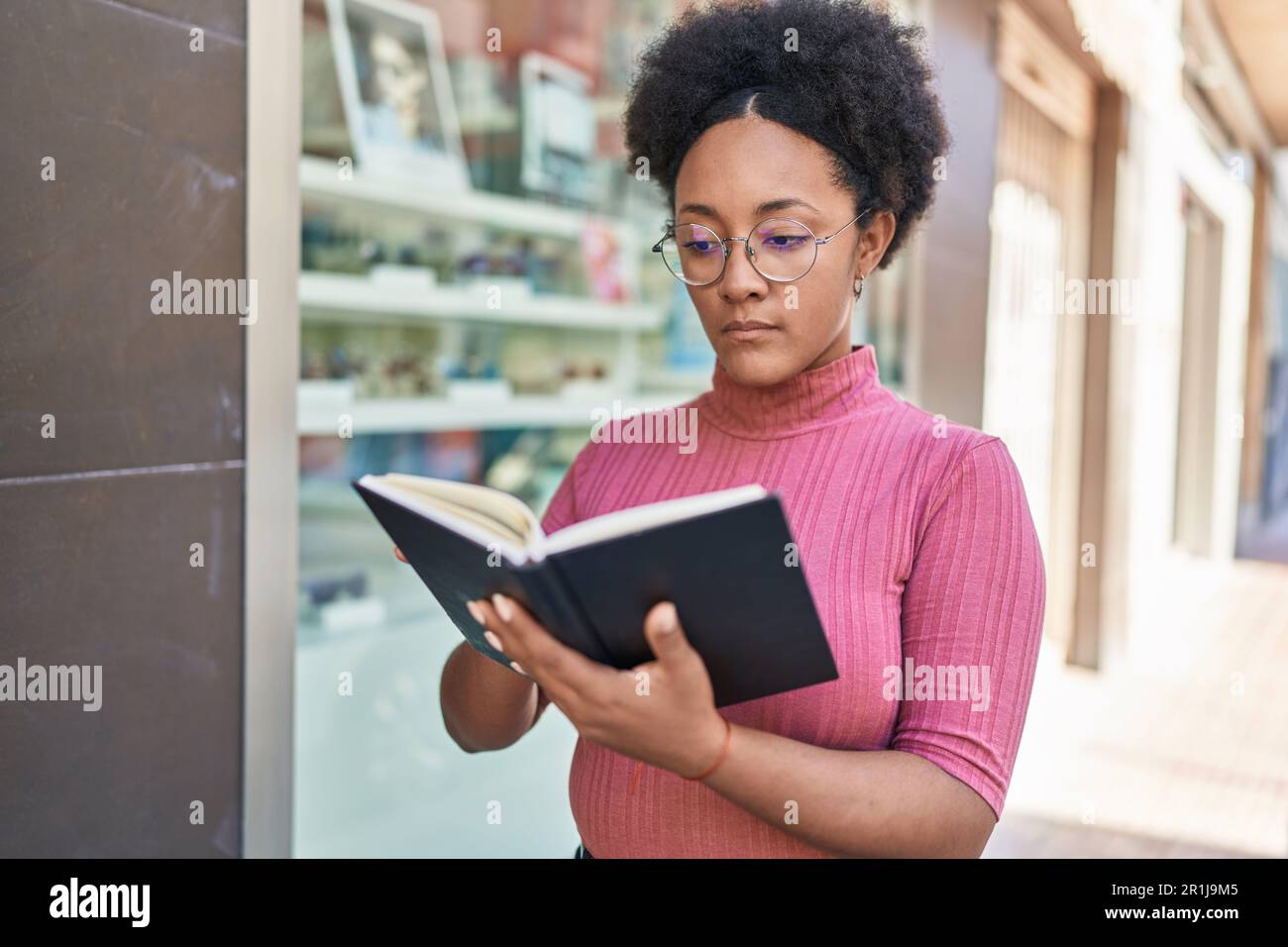 African american woman reading book at street Stock Photo - Alamy