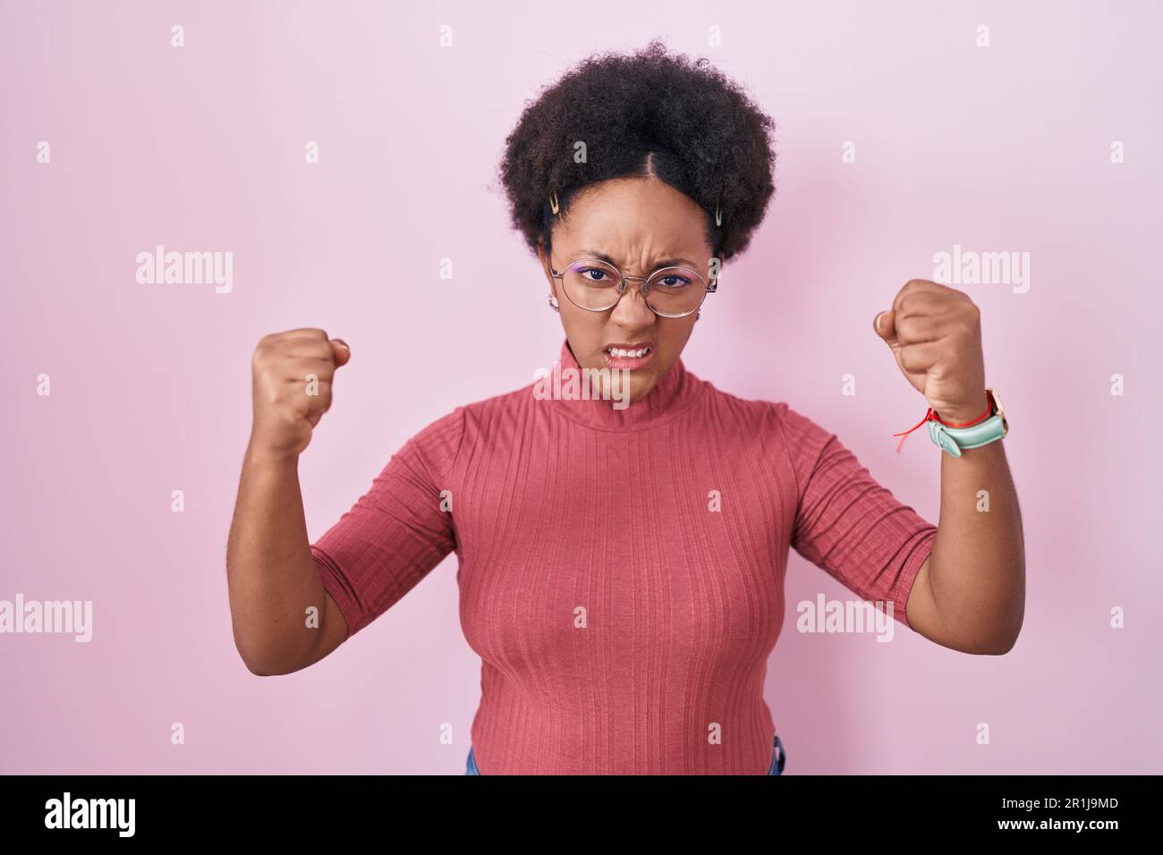 Beautiful african woman with curly hair standing over pink background ...