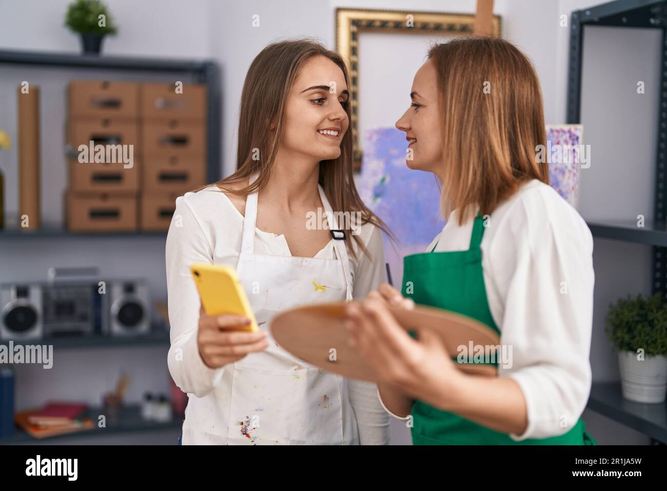 Two women artists smiling confident using smartphone drawing at art ...