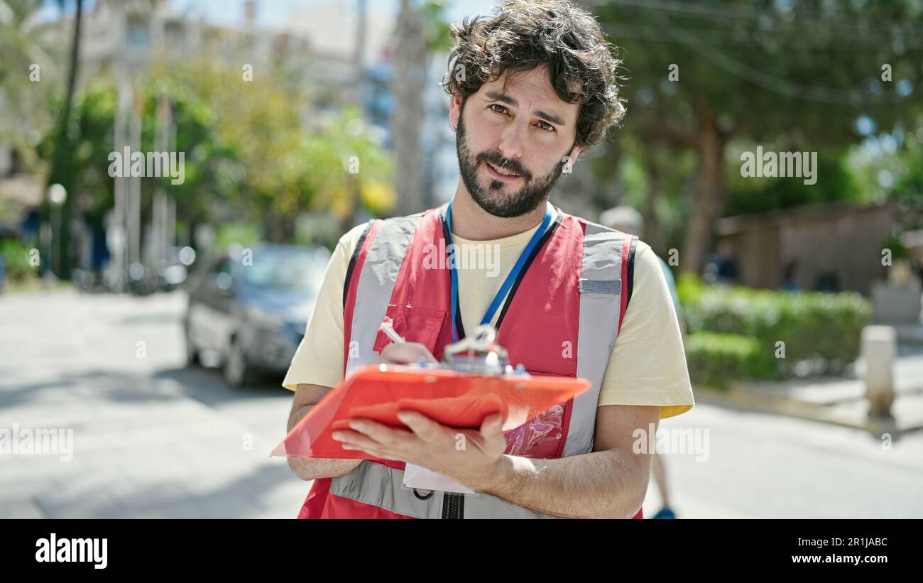 Young hispanic man having survey interview writing on clipboard at ...
