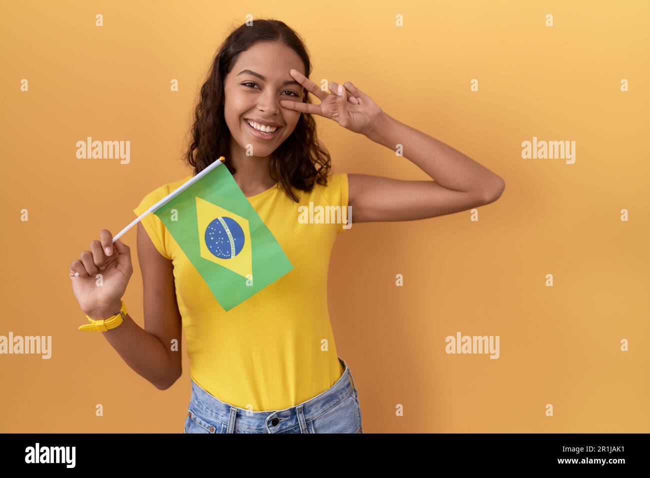 Young hispanic woman holding brazil flag doing peace symbol with ...