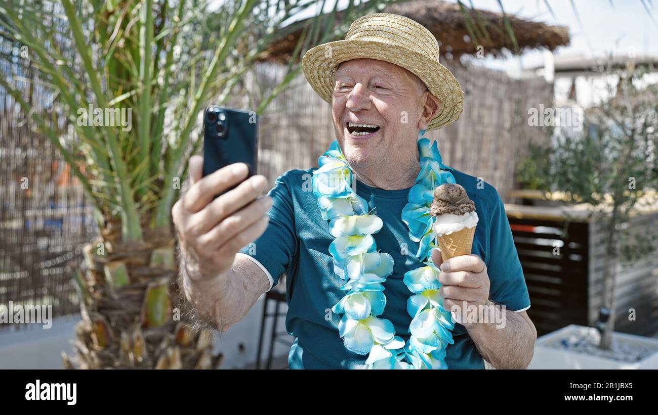 Senior grey-haired man tourist holding ice cream having video call at ...