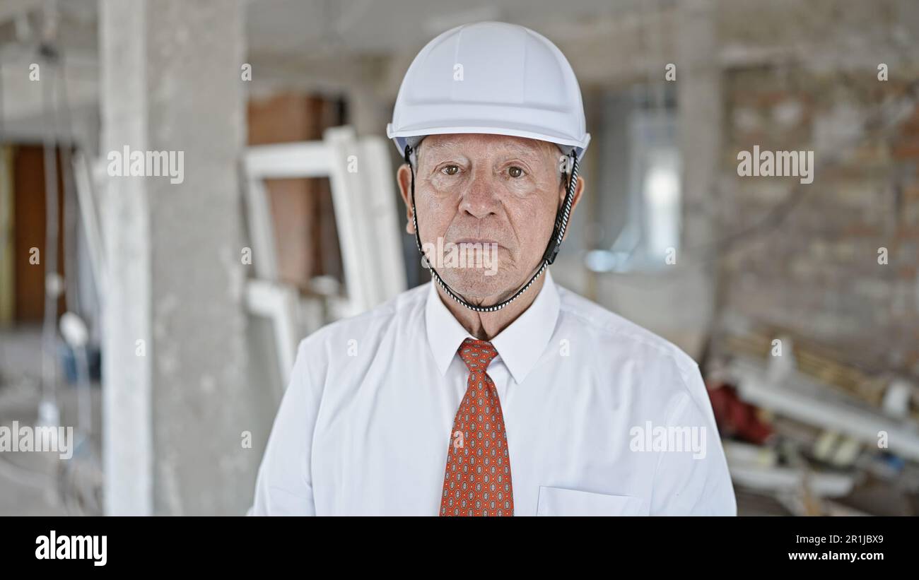 Senior grey-haired man architect standing with relaxed expression at ...
