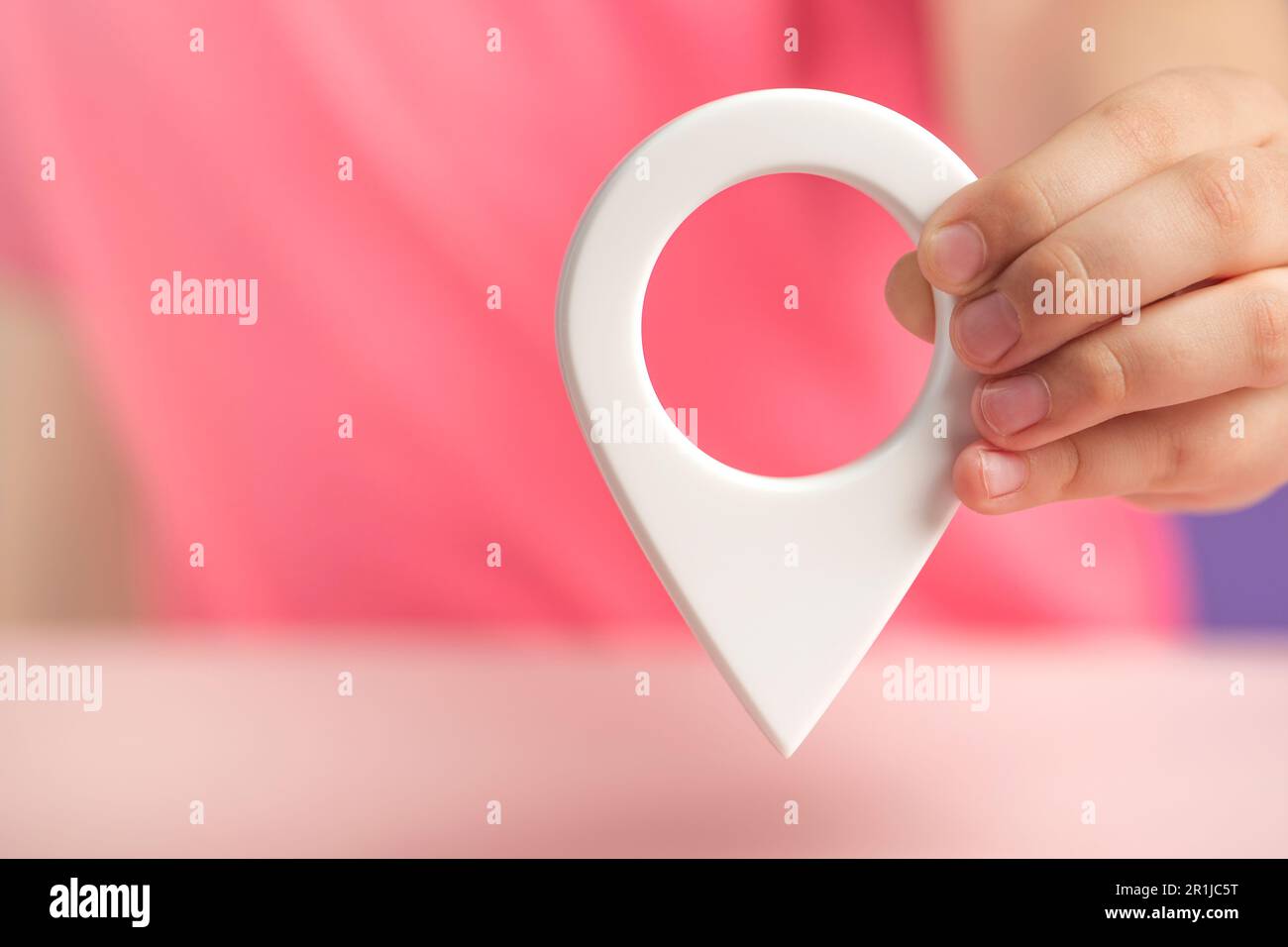 A hand holds a location sign on a purple background. Laying a route ...