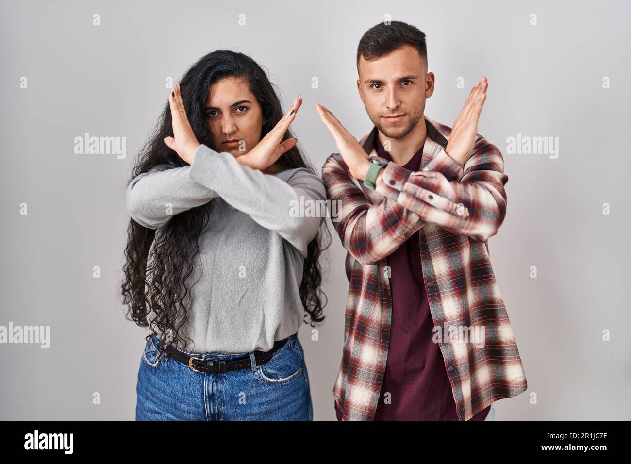 Young hispanic couple standing over white background rejection ...