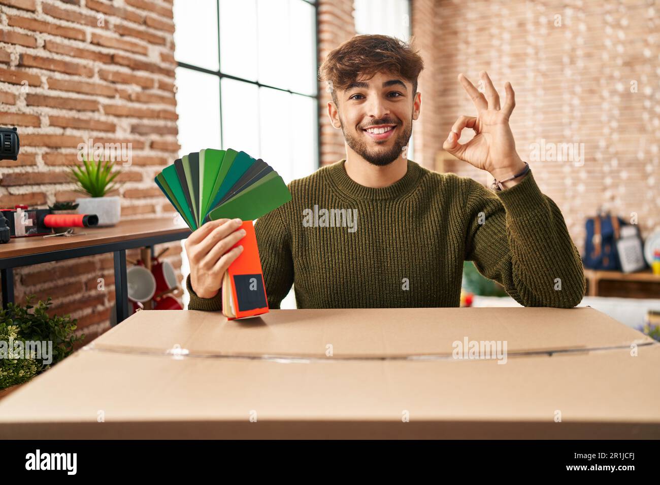 Arab man with beard moving to a new home choosing walls paint doing ok ...