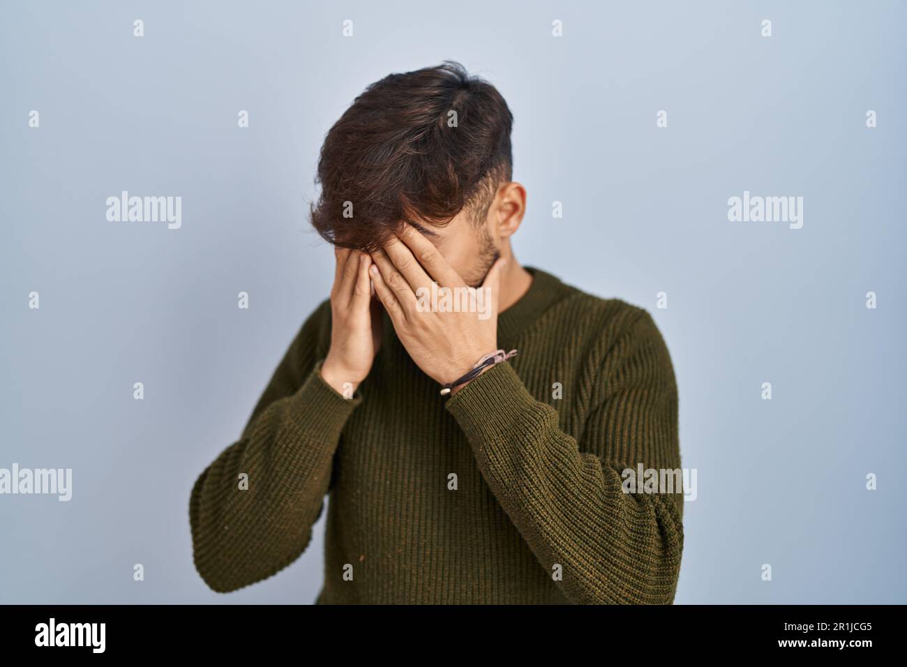 Arab man with beard standing over blue background with sad expression ...