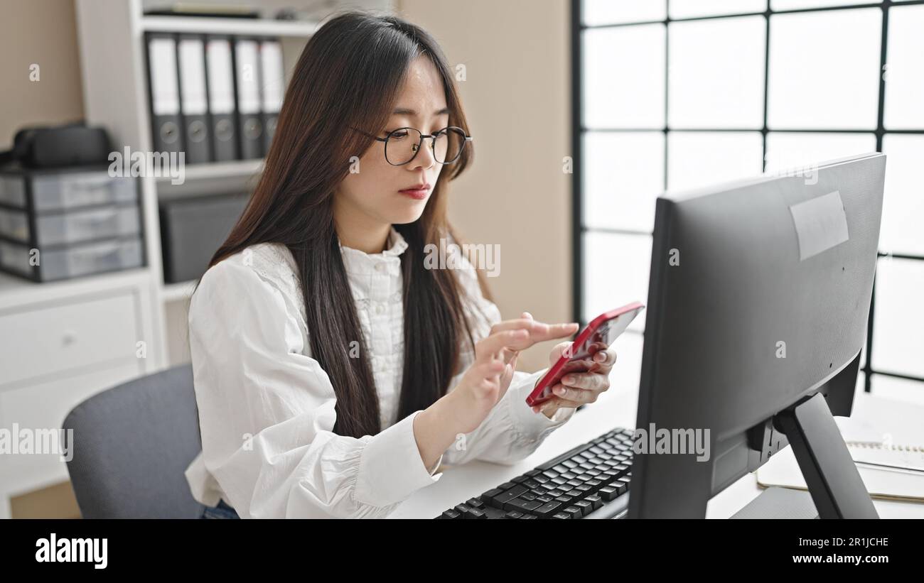 Young chinese woman business worker using computer and smartphone at ...
