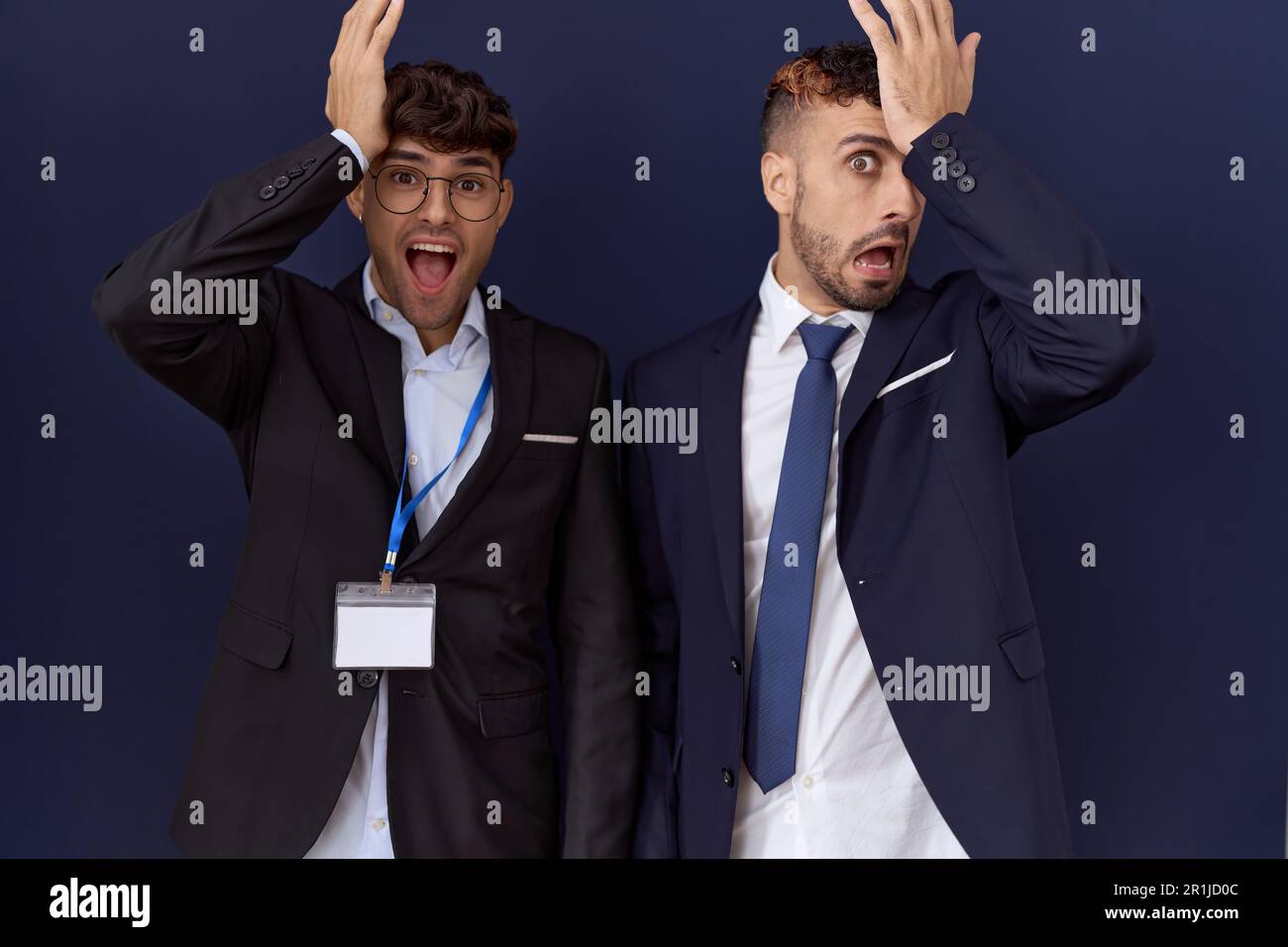 Two hispanic business men wearing business clothes surprised with hand ...