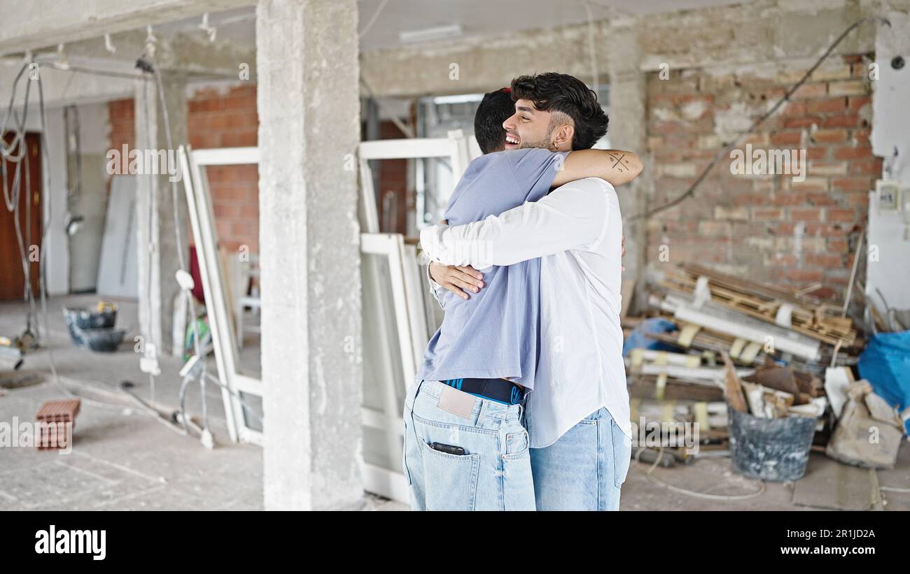 Two men couple smiling confident hugging each other at construction ...