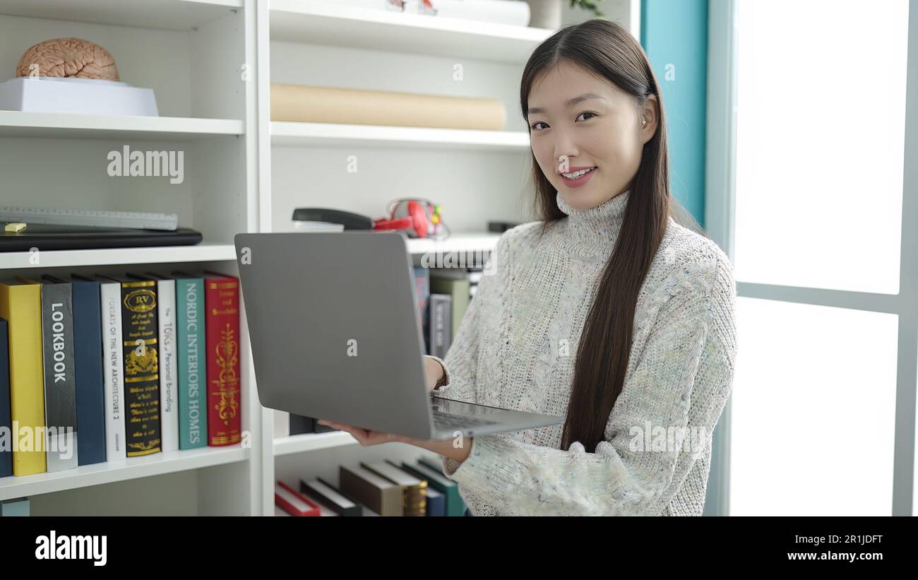 Young chinese woman student using laptop studying at library university ...