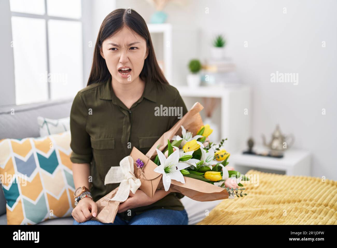 Chinese young woman holding bouquet of white flowers angry and mad ...