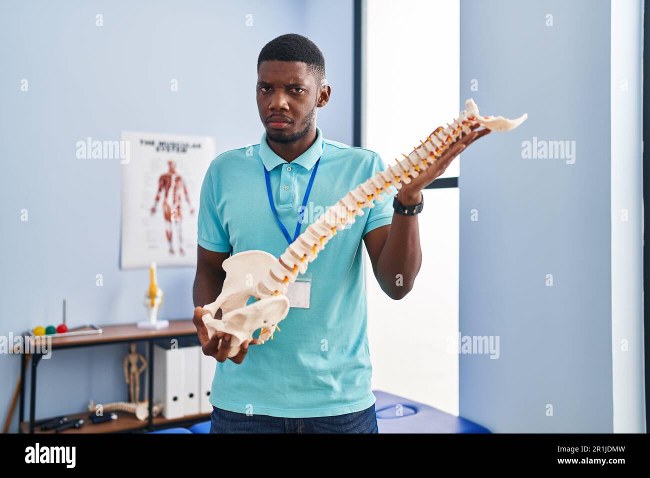 African american man holding anatomical model of spinal column ...