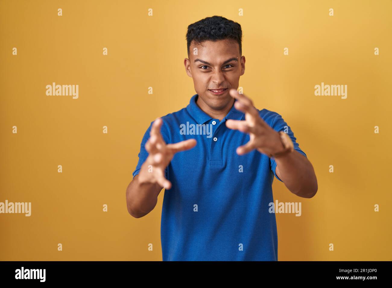 Young hispanic man standing over yellow background shouting frustrated ...