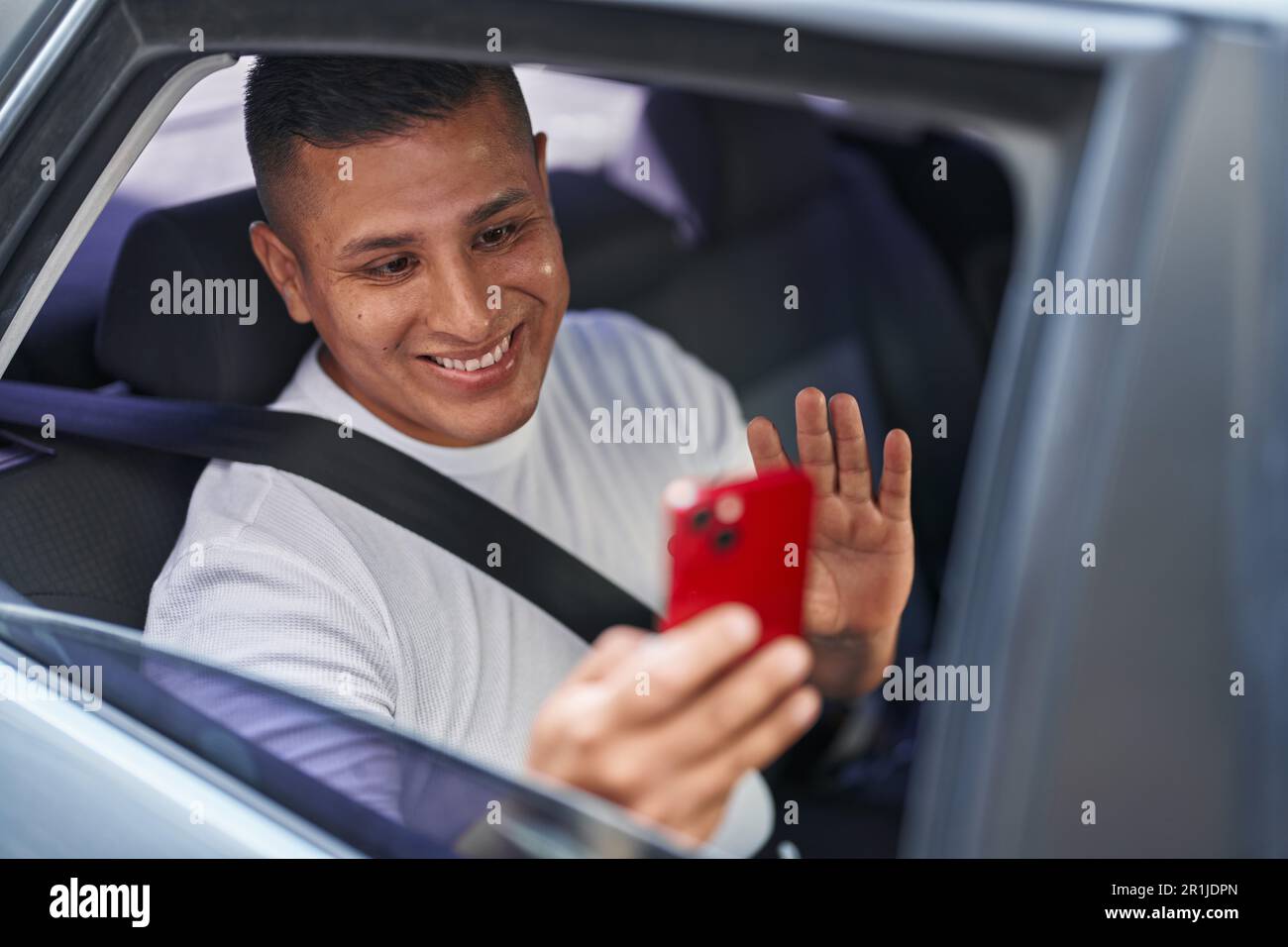 Young hispanic man doing video call with smartphone in the car looking ...