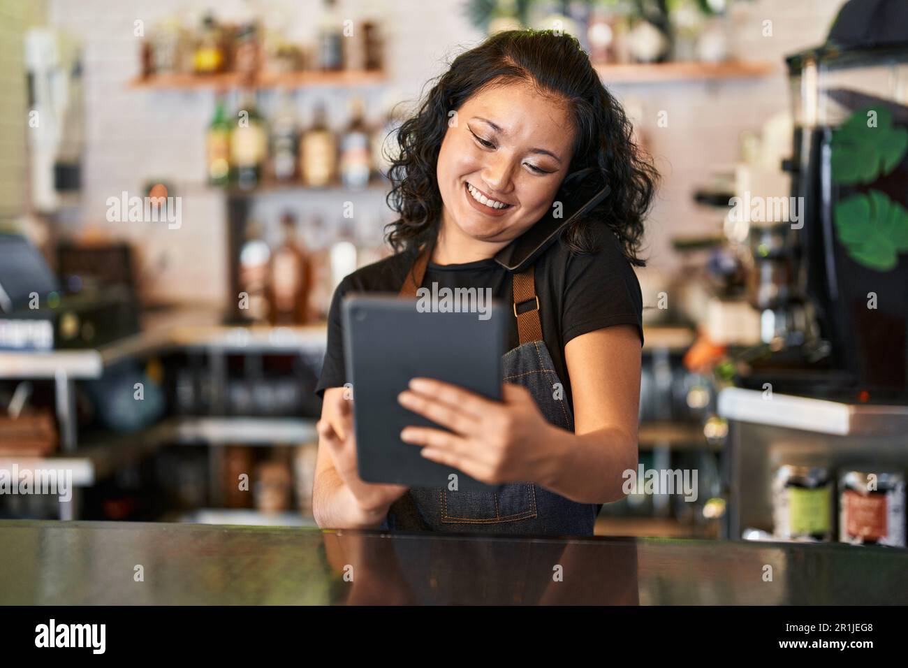 Young chinese woman waitress smiling confident using touchpad at ...
