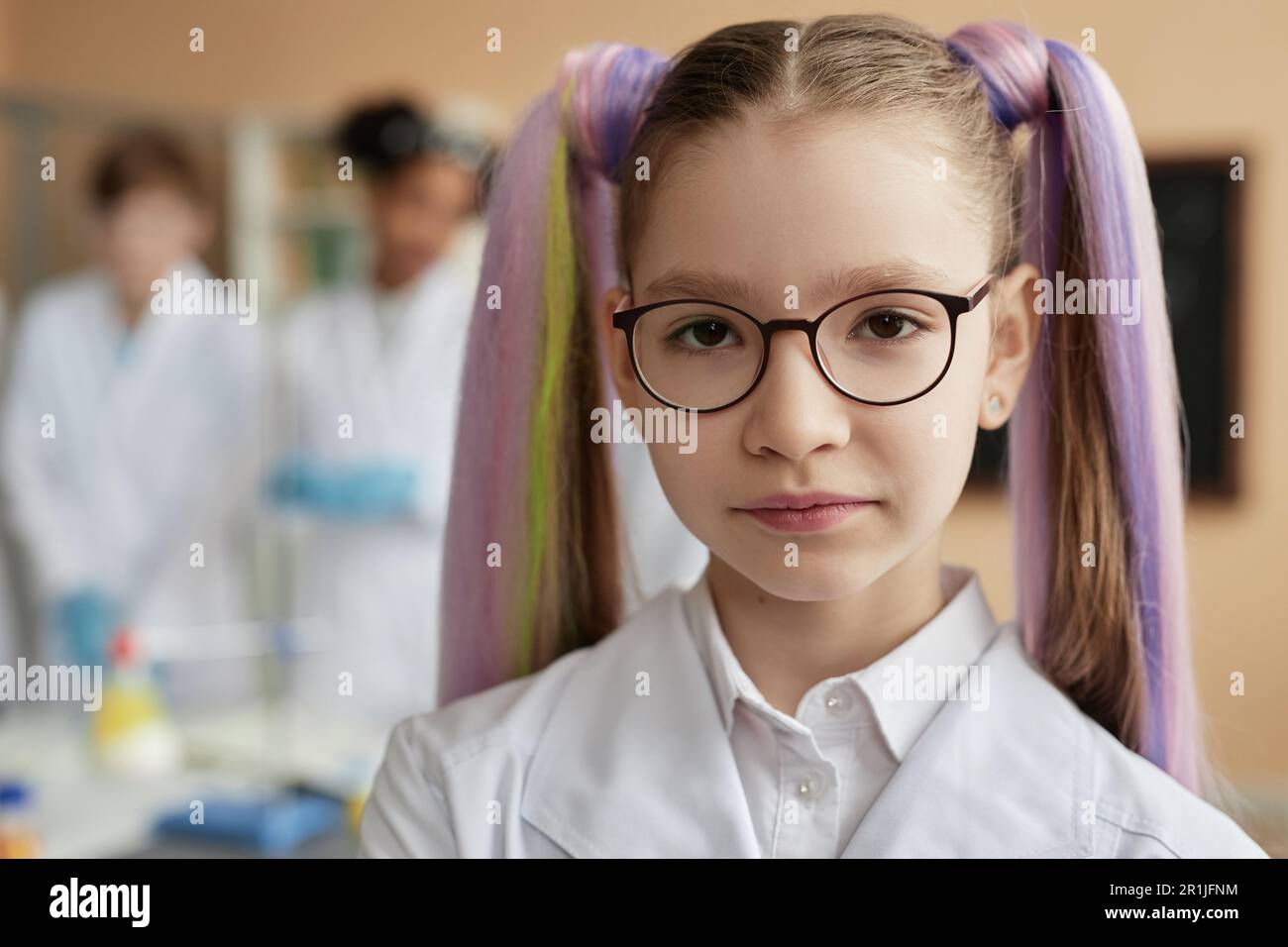 Closeup portrait of cute teen schoolgirl with pigtails wearing lab coat in science class and ...