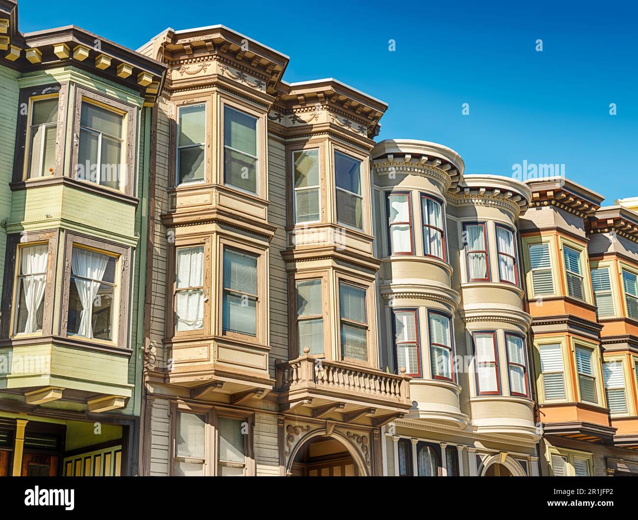 A series of classic colorful painted Victorian homes line a street on ...