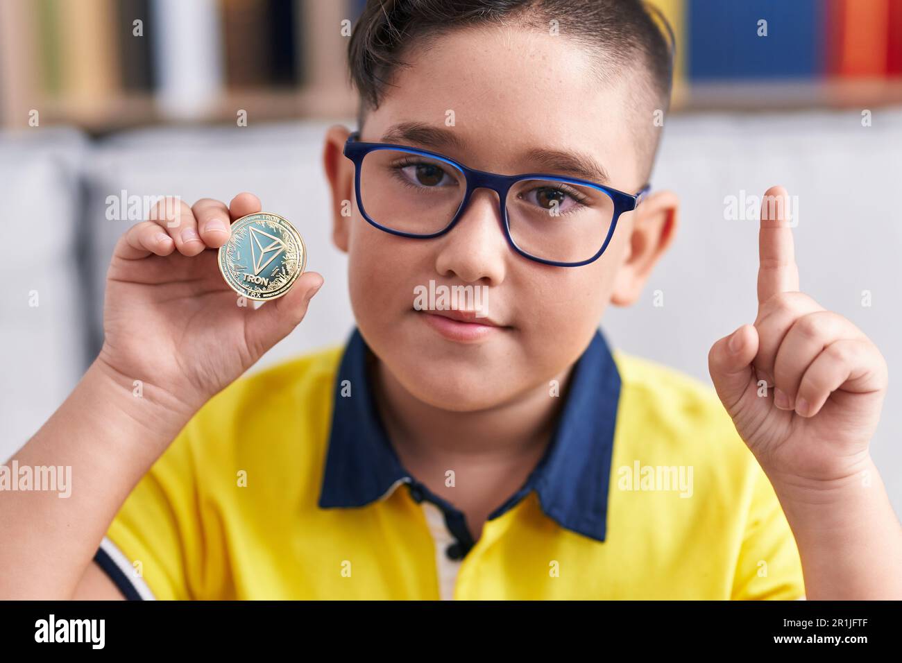 Young hispanic kid holding tron cryptocurrency coin smiling with an ...
