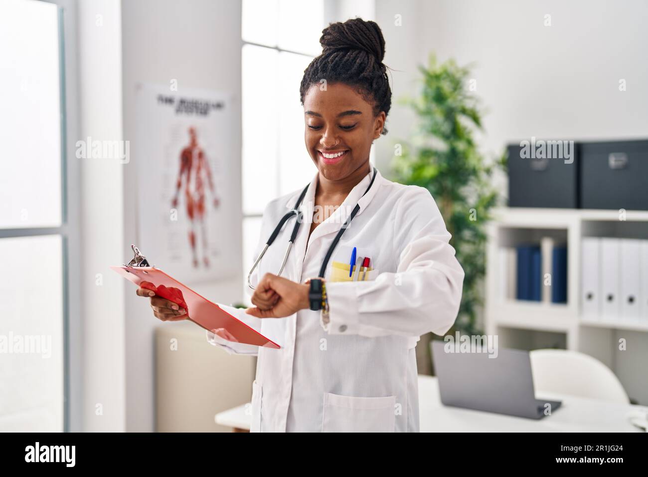 Young african american with braids wearing doctor uniform looking at ...