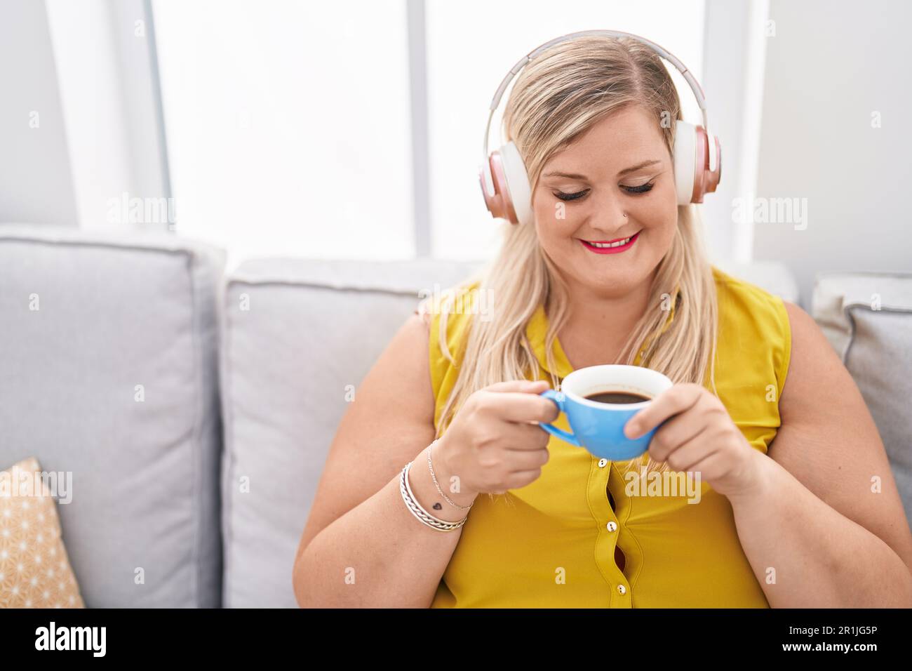 Young woman listening to music drinking coffee at home Stock Photo - Alamy