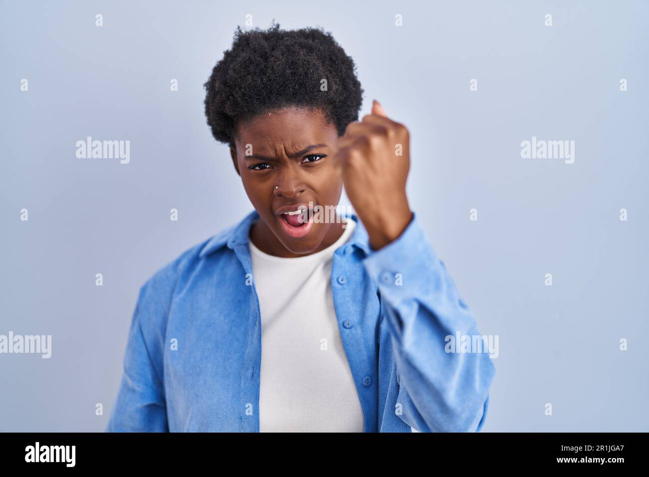 African american woman standing over blue background angry and mad ...