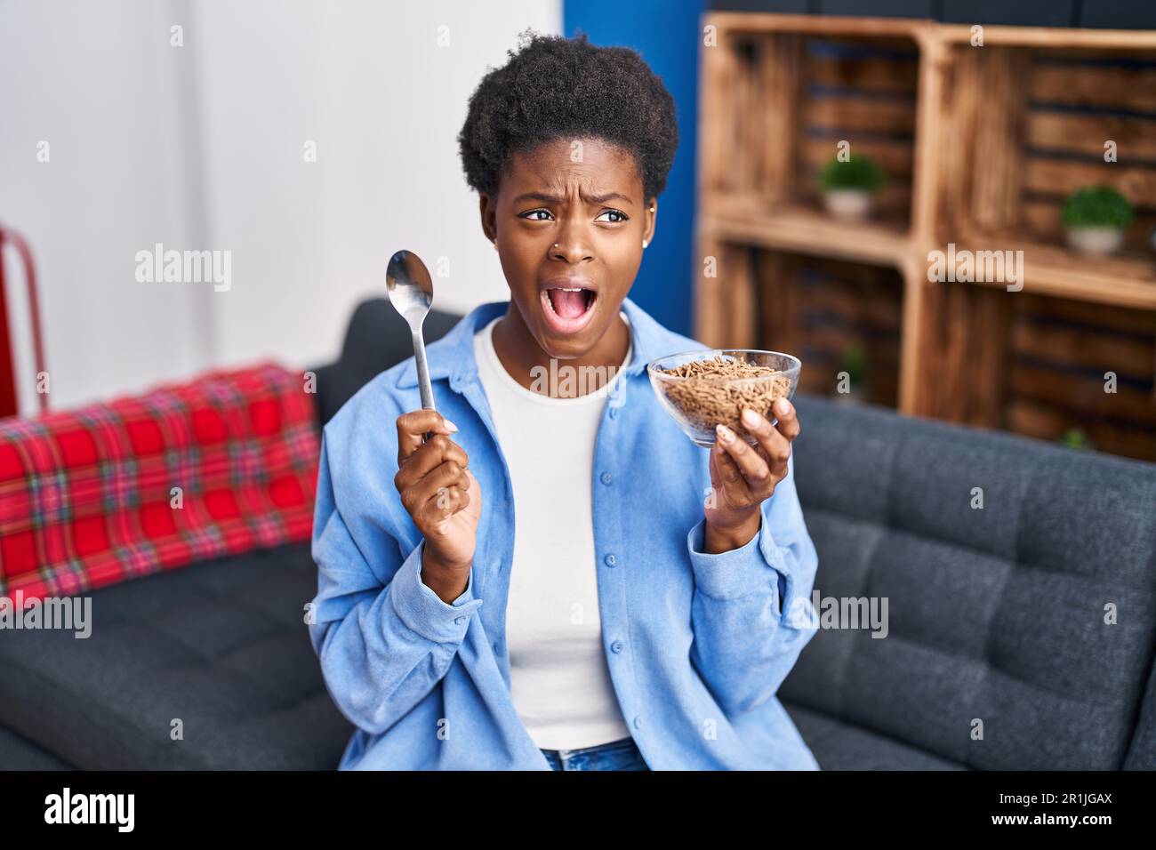African american woman eating healthy whole grain cereals angry and mad ...