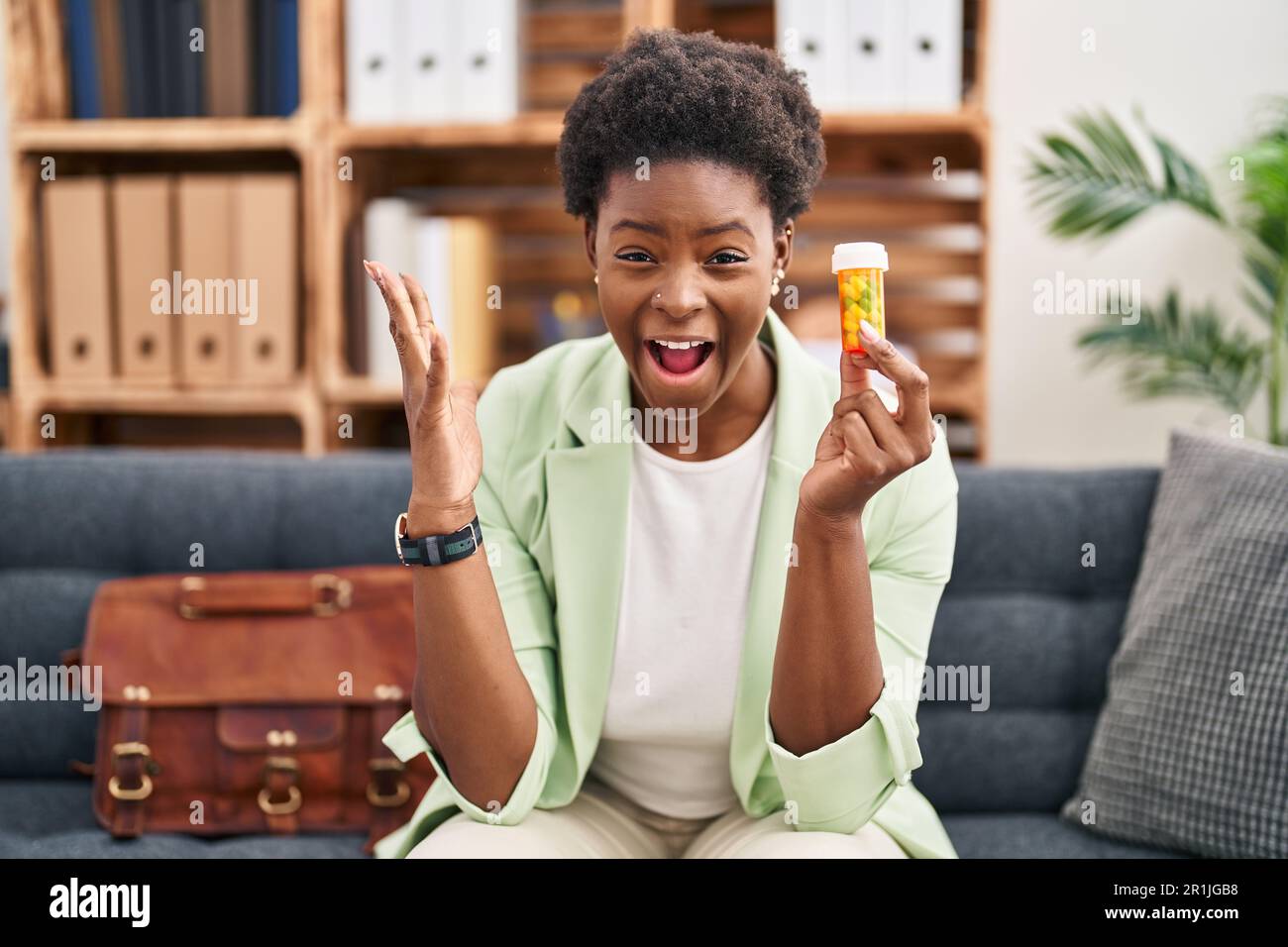 African american woman working on depression holding pills celebrating ...