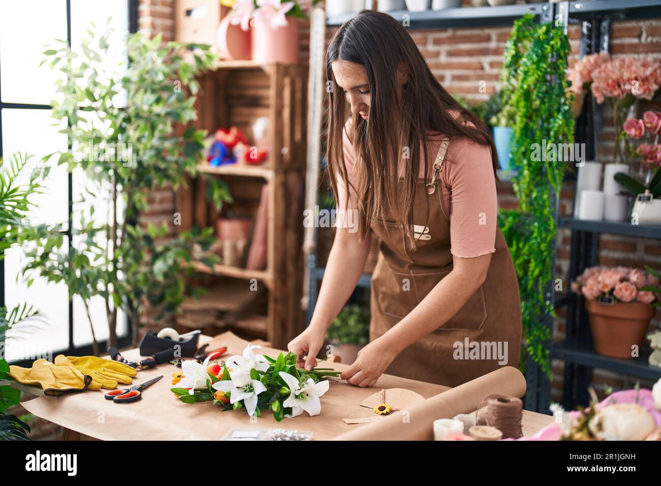 Young beautiful hispanic woman florist make bouquet of flowers at ...