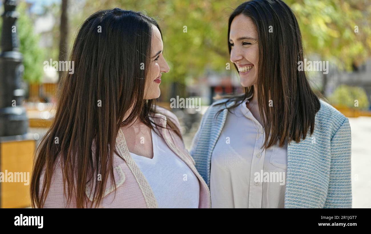 Two women smiling confident standing together at park Stock Photo - Alamy