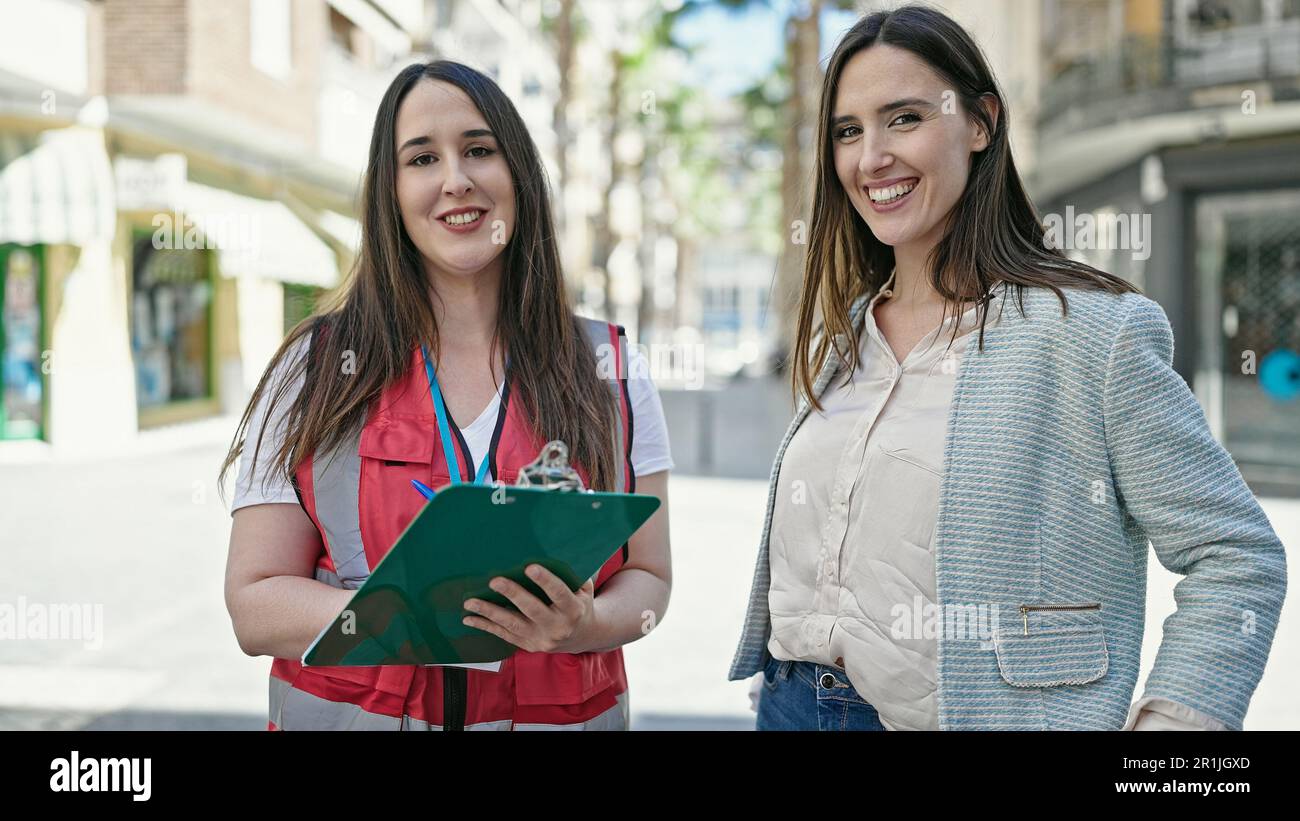 Two women having survey interview writing on clipboard at street Stock ...