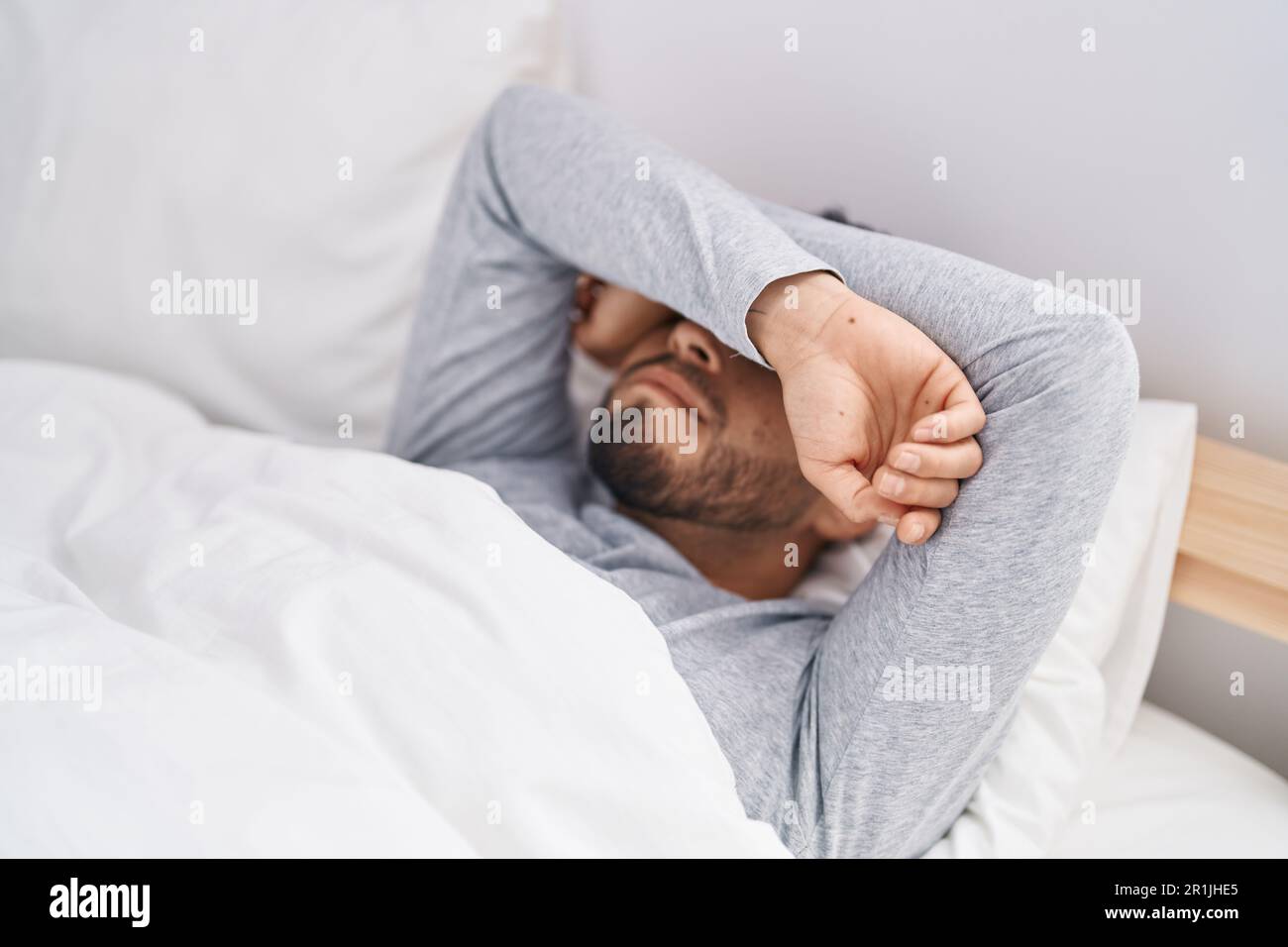 Young hispanic man lying on bed crying at bedroom Stock Photo - Alamy
