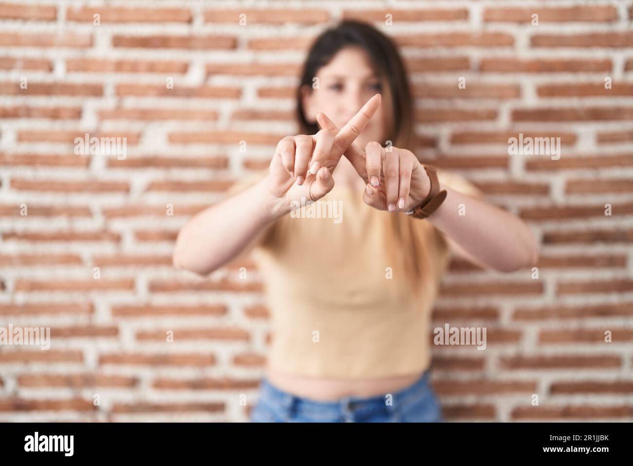 Young Brunette Woman Standing Over Bricks Wall Rejection Expression