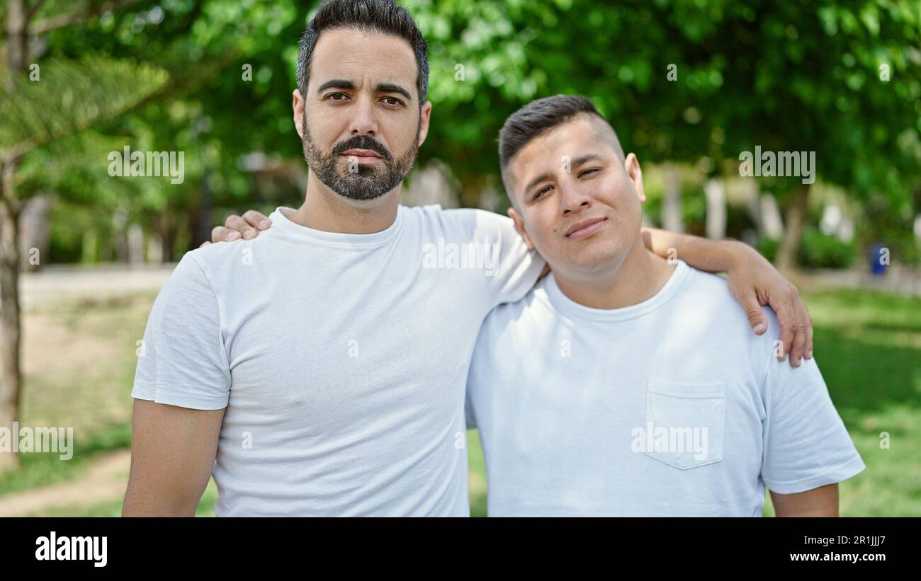 Two men hugging each other with relaxed expression at park Stock Photo ...